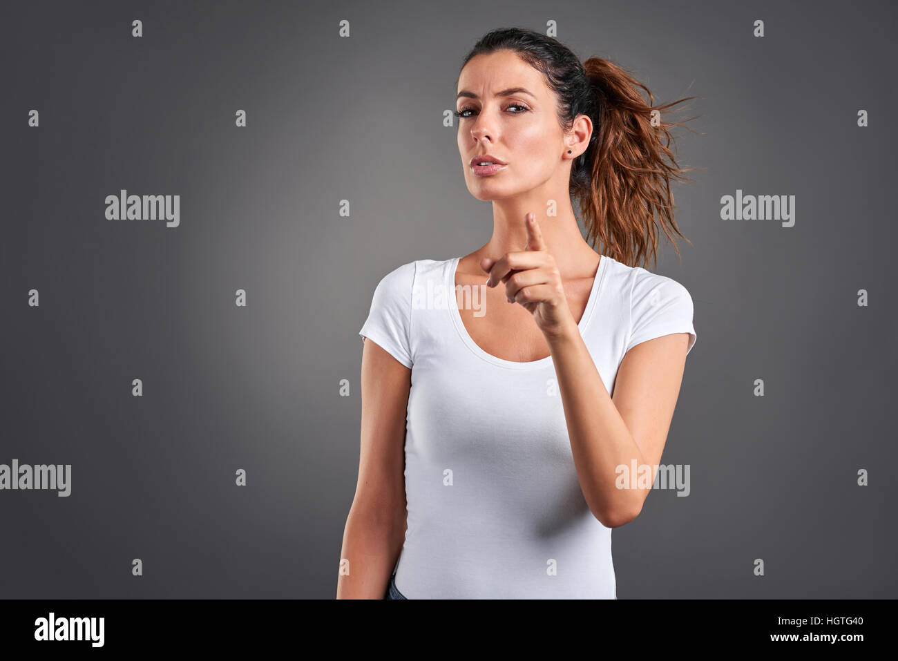 A beautiful young woman feeling suspicious and pointing in to the ...