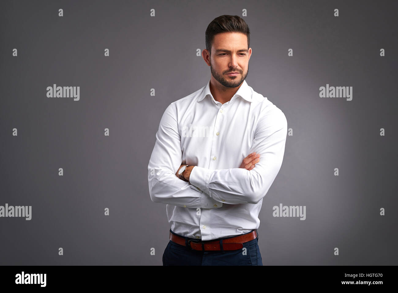 A handsome confident young man standing seriously in a white shirt ...