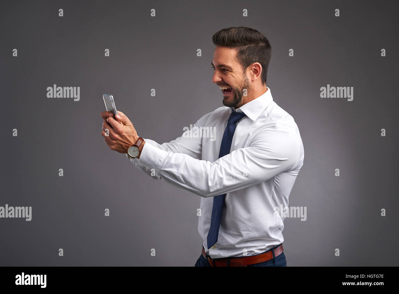 A handsome young man holding his phone and screaming to it wearing a ...