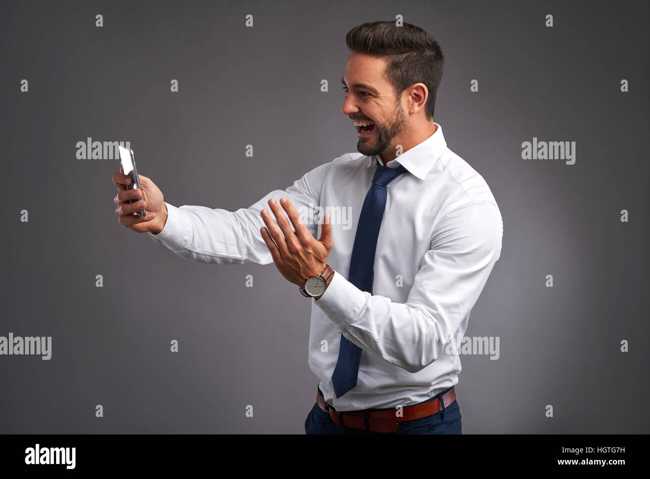 A handsome young man holding his phone and screaming to it wearing a ...