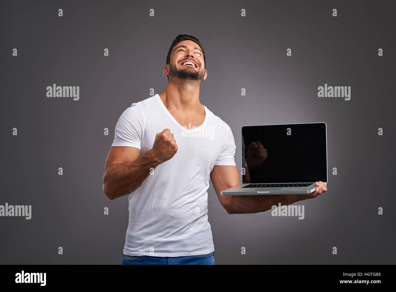 A handsome young man holding and showing the screen of a laptop and ...