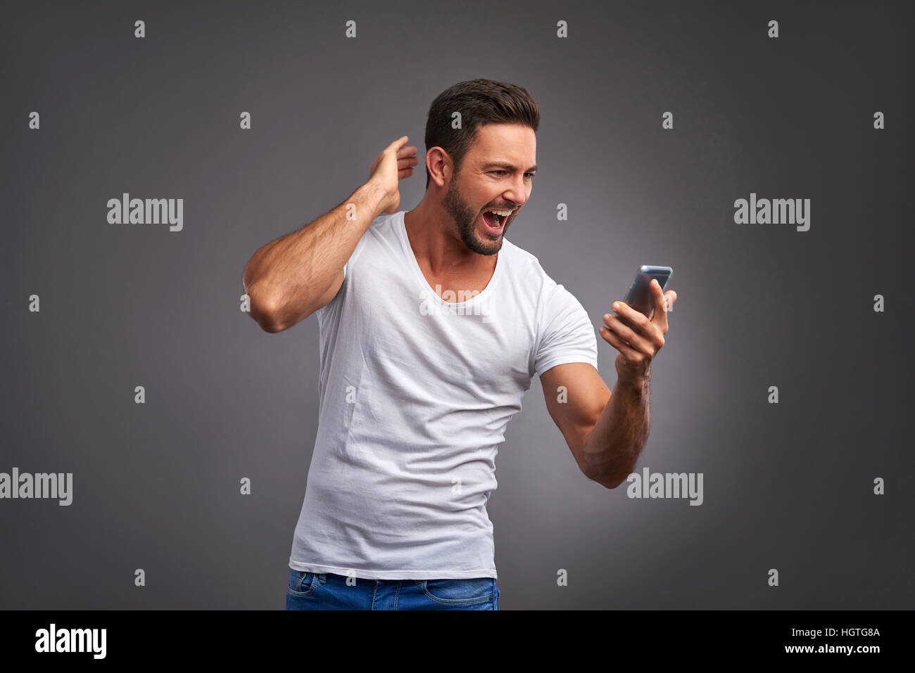 A handsome young man screaming to a smartphone in his hand Stock Photo ...