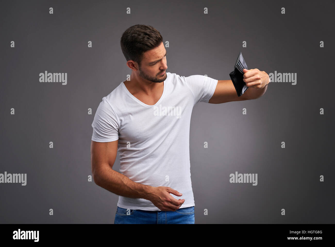 A poor handsome young man feeling stressed while looking at his empty ...