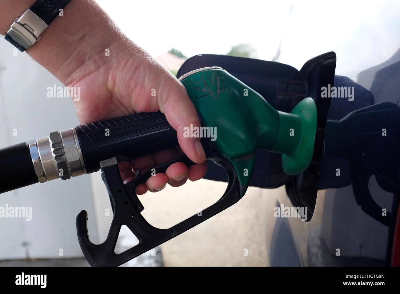 mans hand holding petrol pump nozzle into car tank filling up at gas ...
