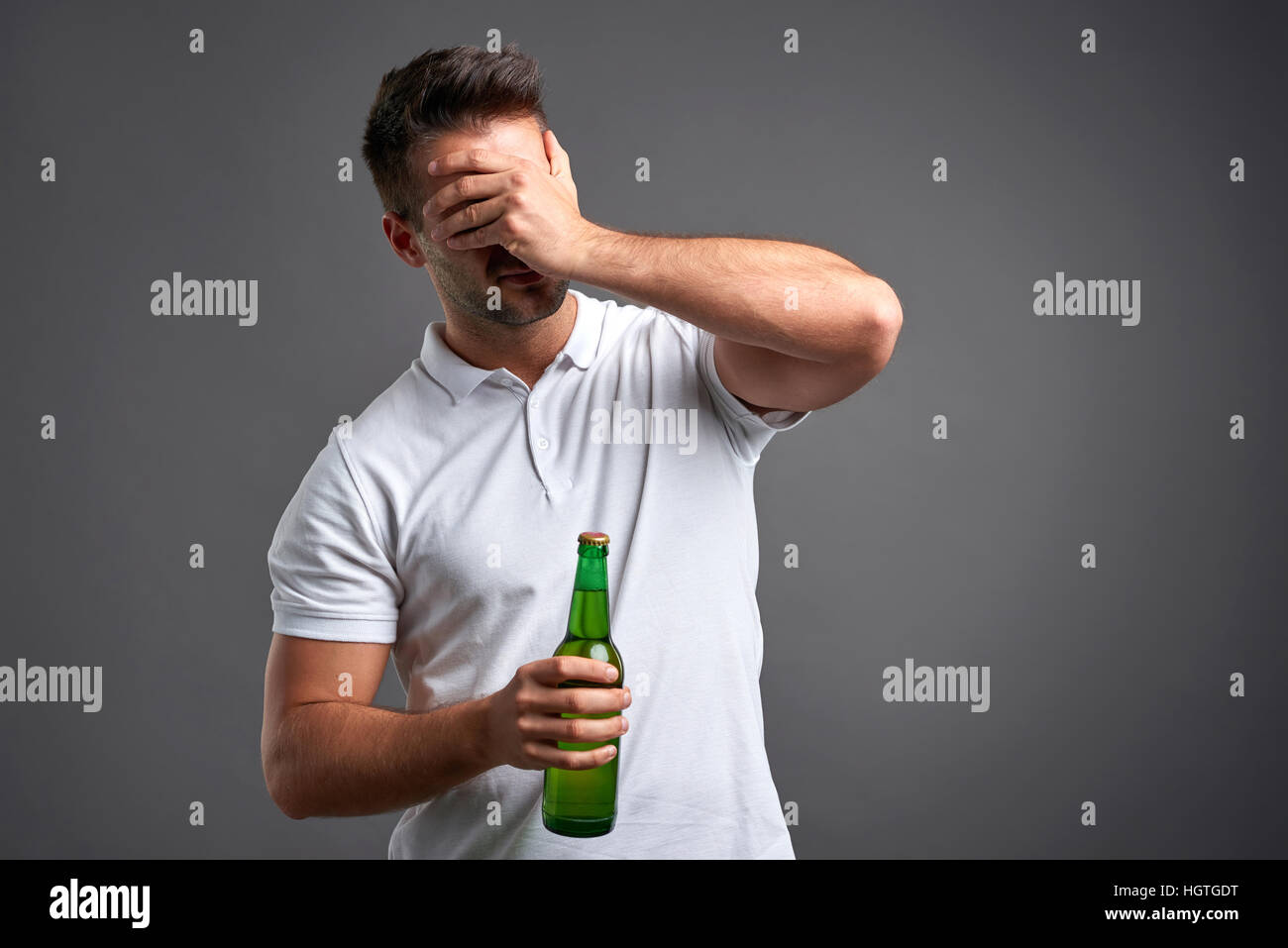 A handsome young man feeling desperate and grabbing his head while ...