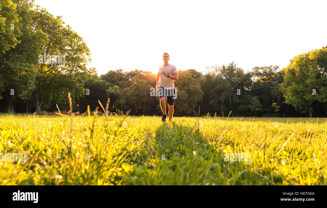 A handsome young man running on a summer evening in the sunset in a ...