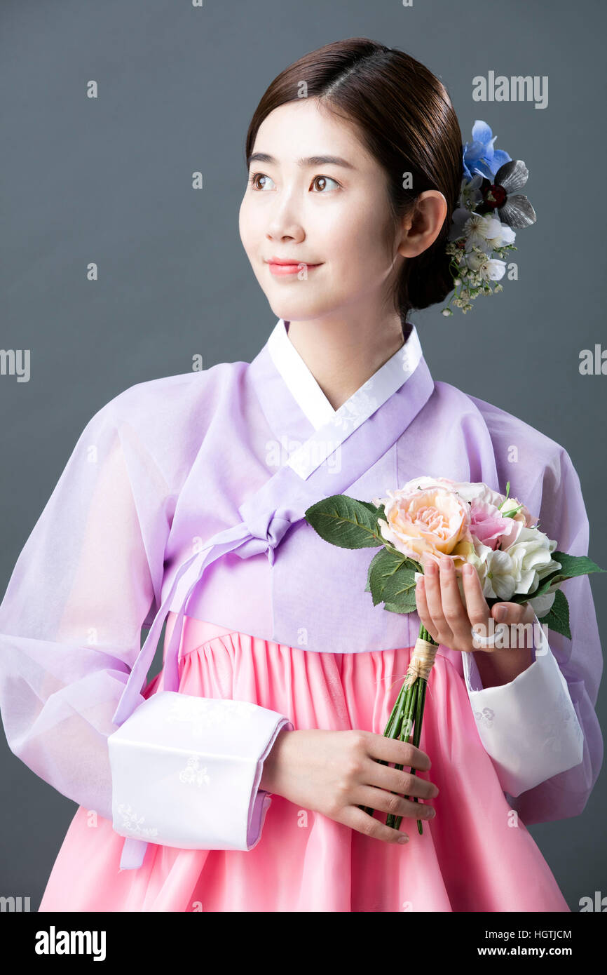 Portrait of young smiling bride in traditional Korean clothes holding ...