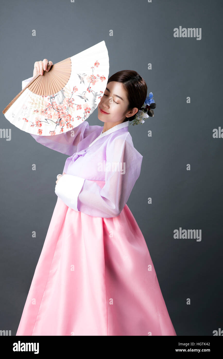 Side view of young woman in traditional Korean clothes posing with ...