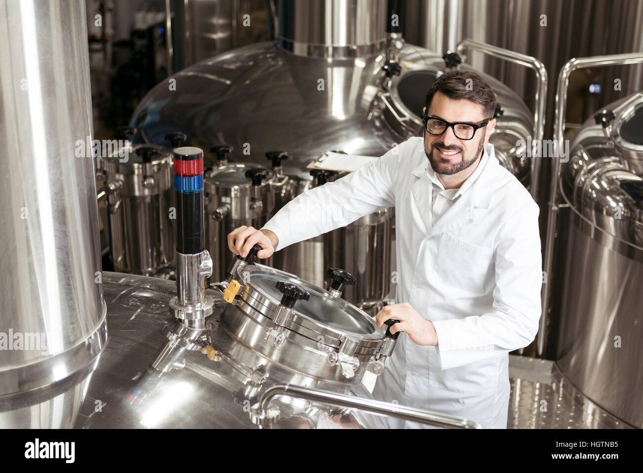 Smiling man using brewing mechanism at factory Stock Photo - Alamy