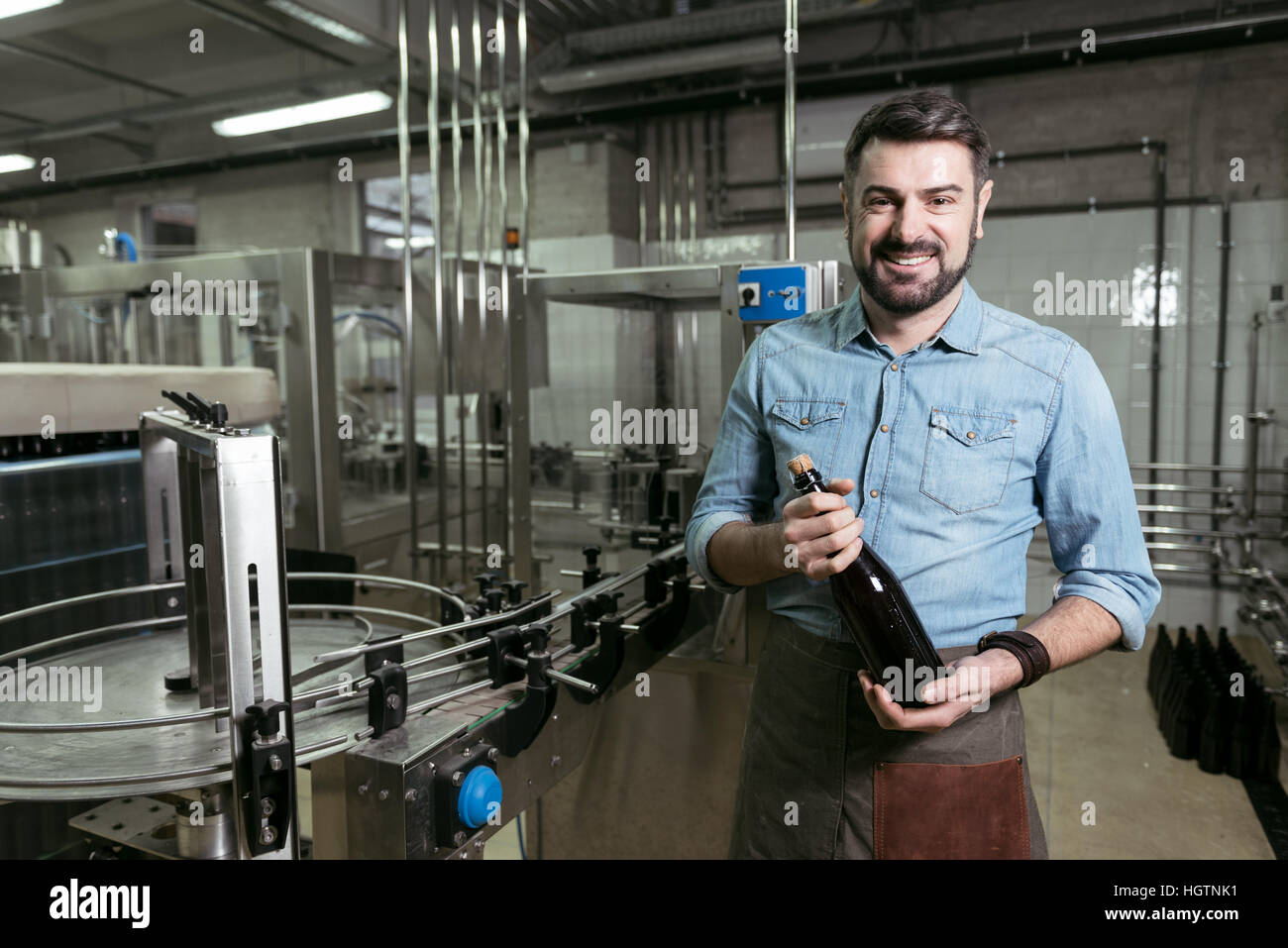 Smiling man holding a bottle of alcohol at brewing factory Stock Photo ...