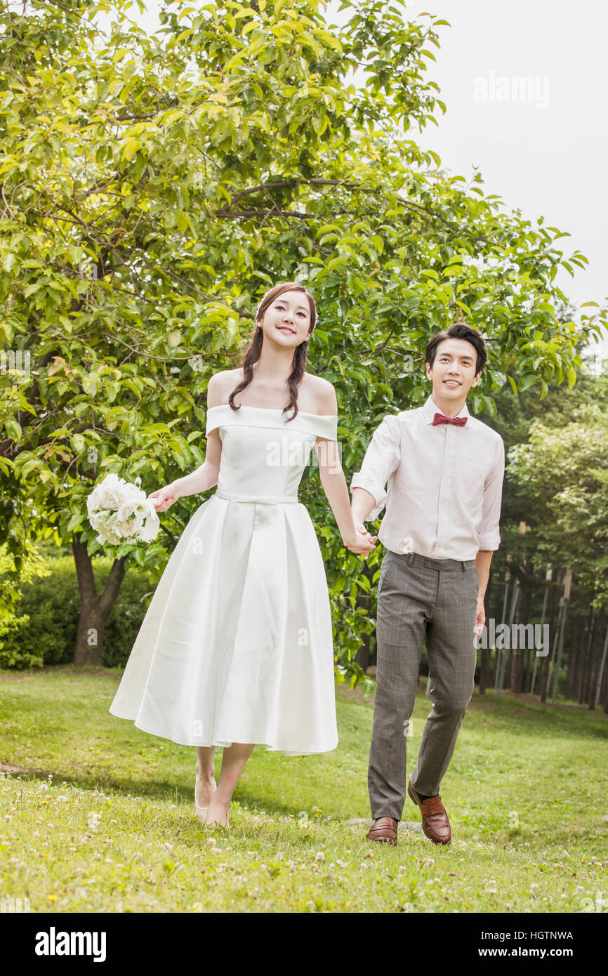 Young smiling wedding couple running hand in hand outdoors Stock Photo ...