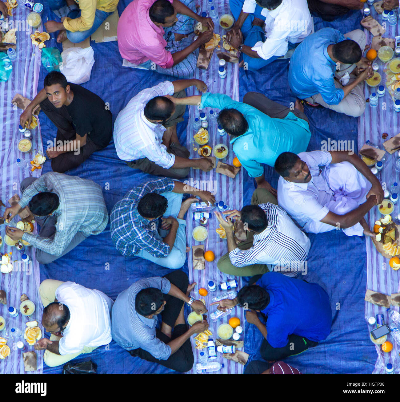 Muslim men gathering for a communal charity iftar organised on a street ...
