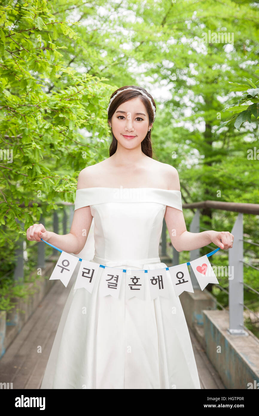 Young bride posing with Korean message outdoors Stock Photo - Alamy