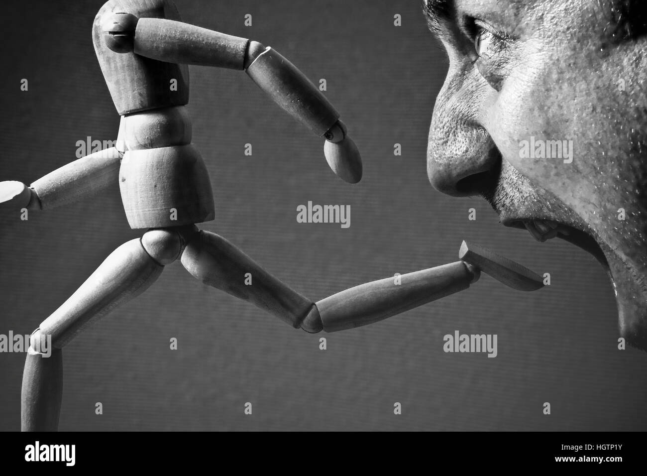 Man bites the foot of a wooden dummy Stock Photo - Alamy