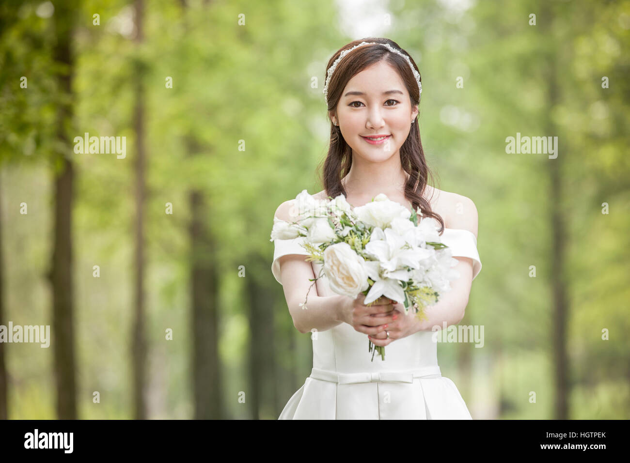 Young smiling bride holding flowers outdoors Stock Photo - Alamy