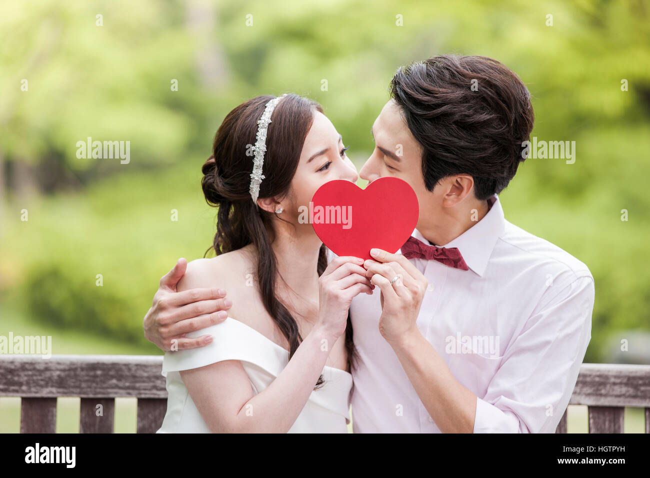 Portrait of young romantic wedding couple face to face with heart ...