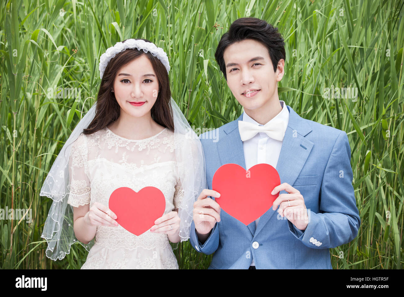 Portrait of smiling wedding couple holding hearts outdoors Stock Photo ...