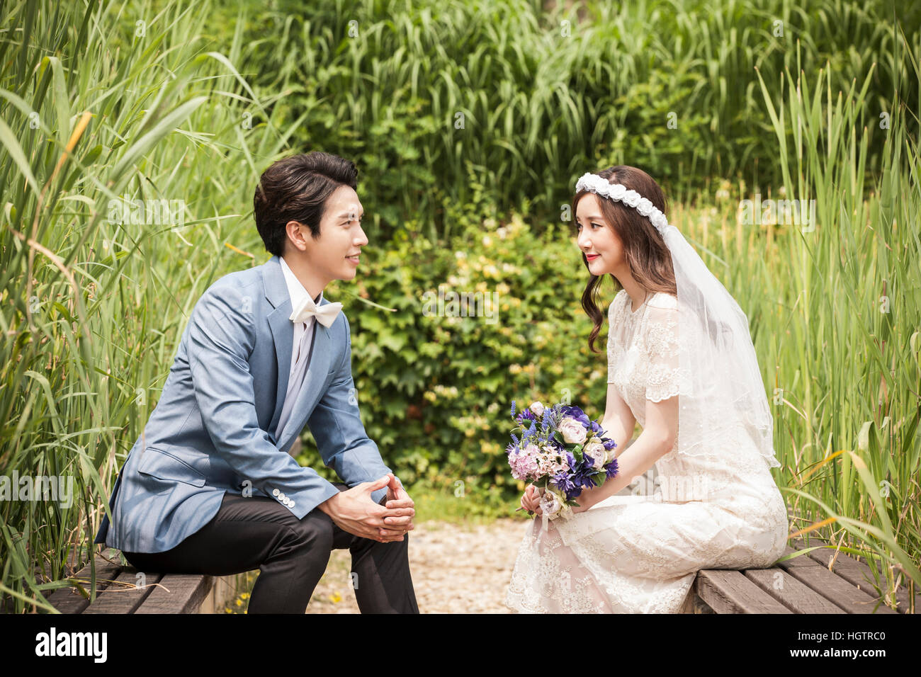 Side view of young wedding couple sitting face to face outdoors Stock ...
