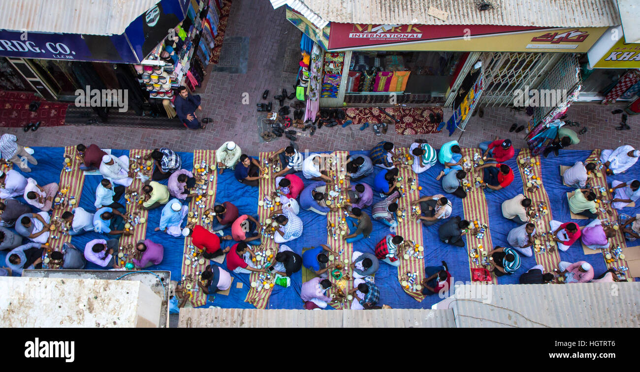 Muslim men gathering for a communal charity iftar organised on a street ...