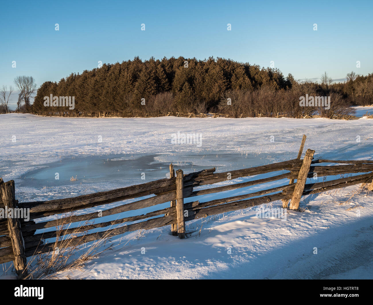 Sun Over Snow covered field with cedar fence in winter Stock Photo - Alamy