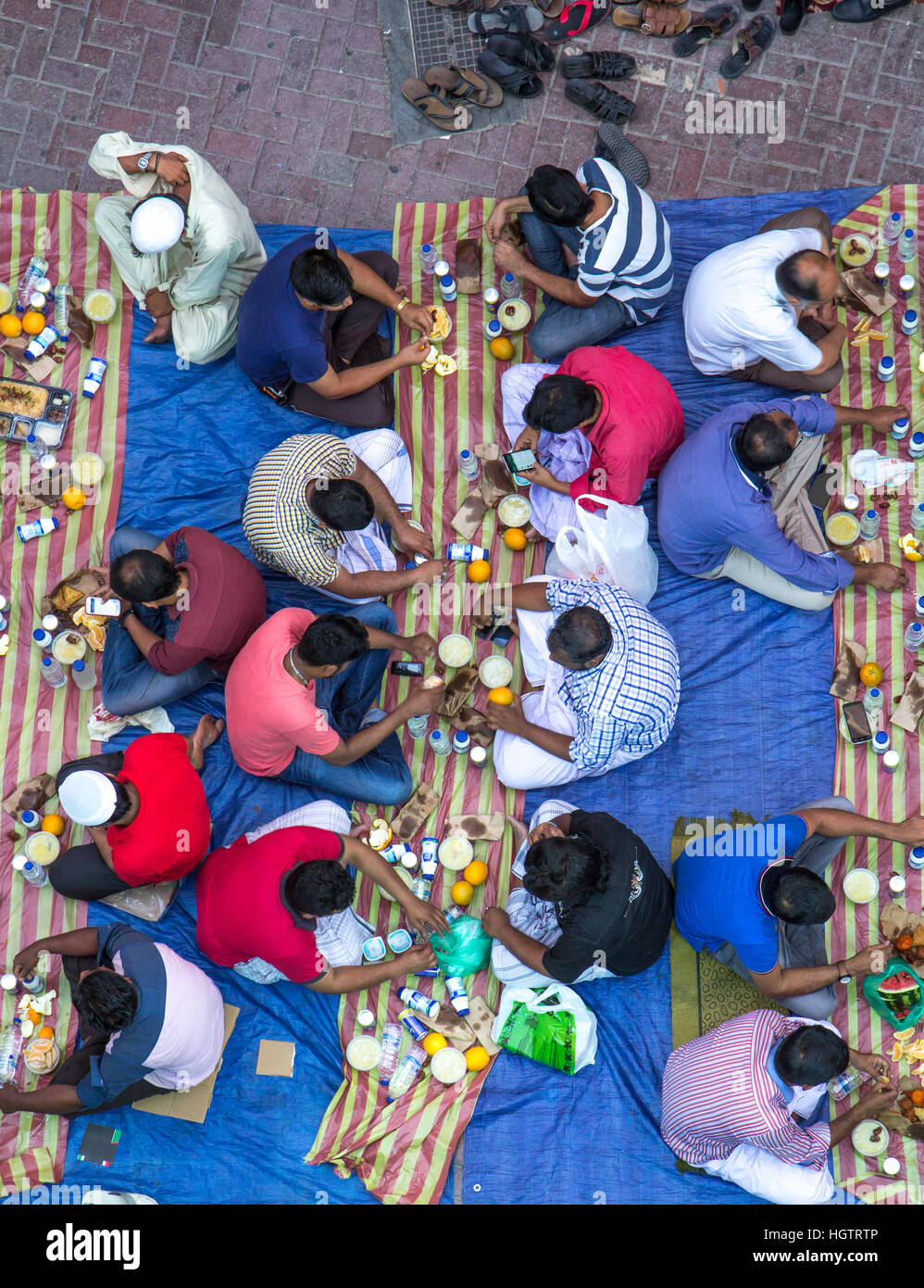 Muslim men gathering for a communal charity iftar organised on a street ...