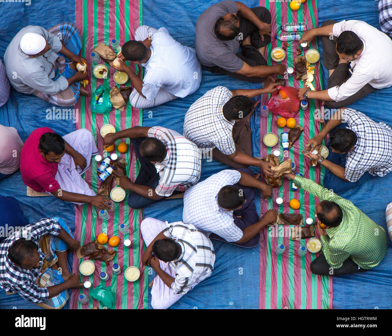 Muslim men gathering for a communal charity iftar organised on a street ...