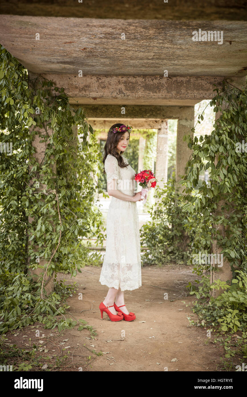 Side view of young smiling bride with flowers standing outdoors Stock Photo - Alamy