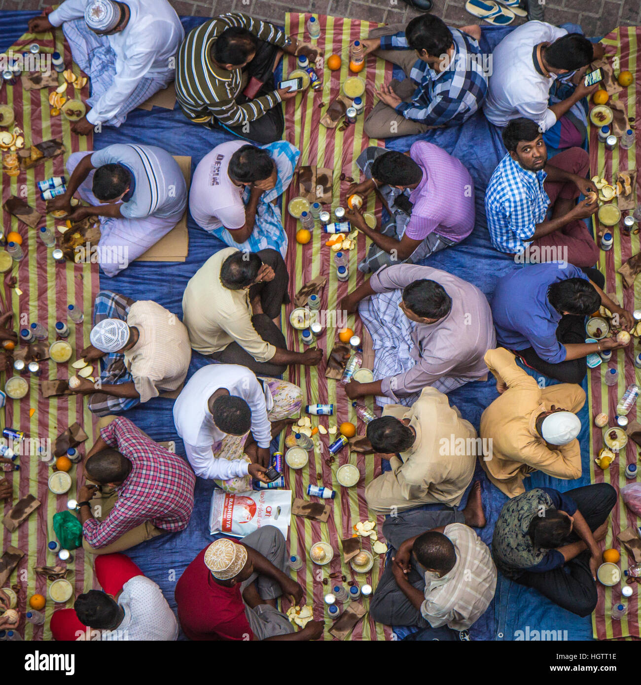 Muslim men gathering for a communal charity iftar organised on a street ...