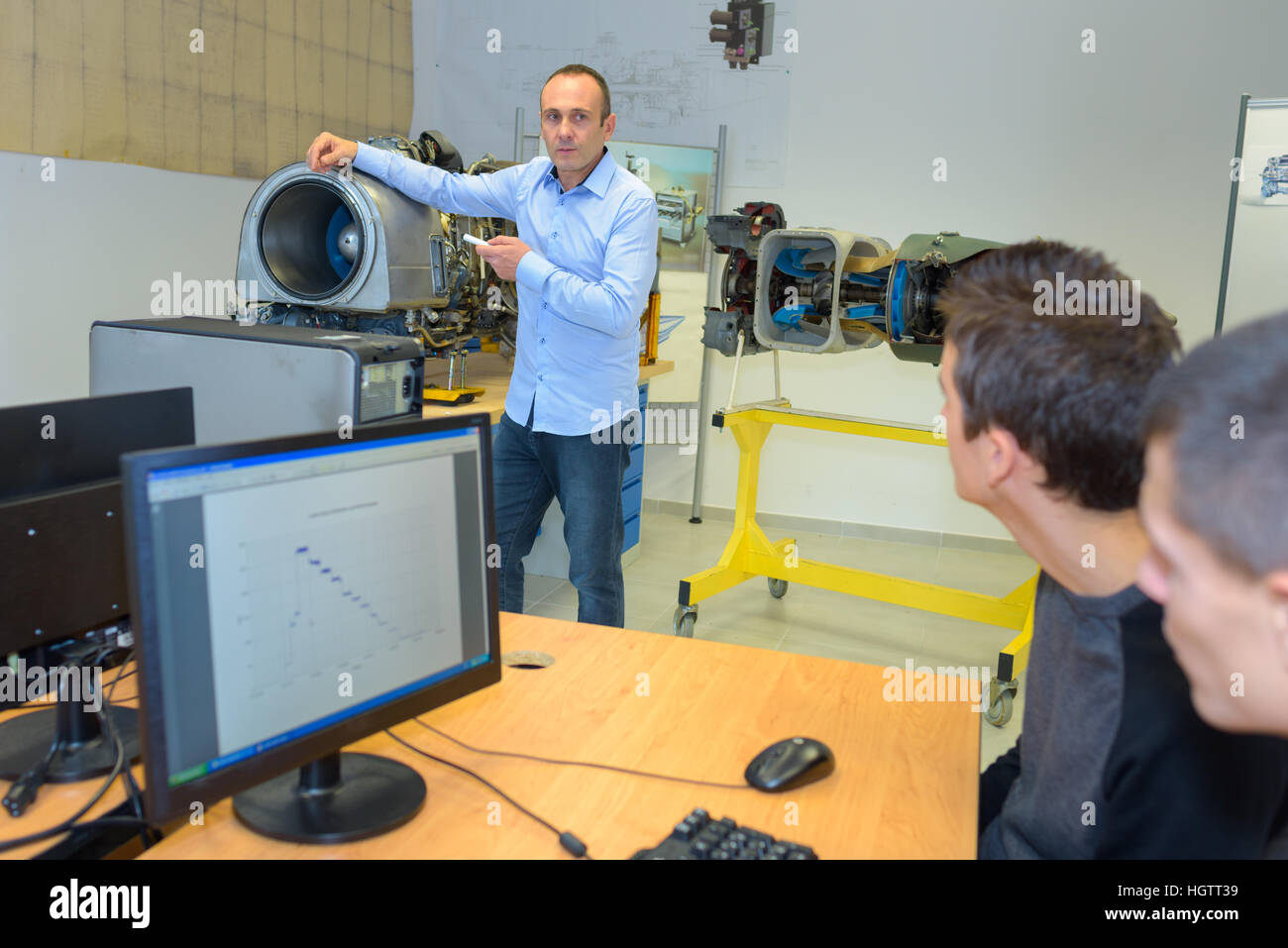 Students at computer looking at teacher with model Stock Photo - Alamy