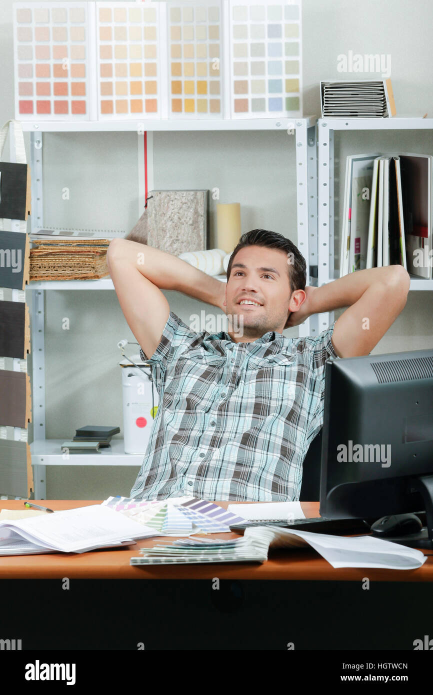 Man sat at desk, leaning back hands behind his head Stock Photo - Alamy
