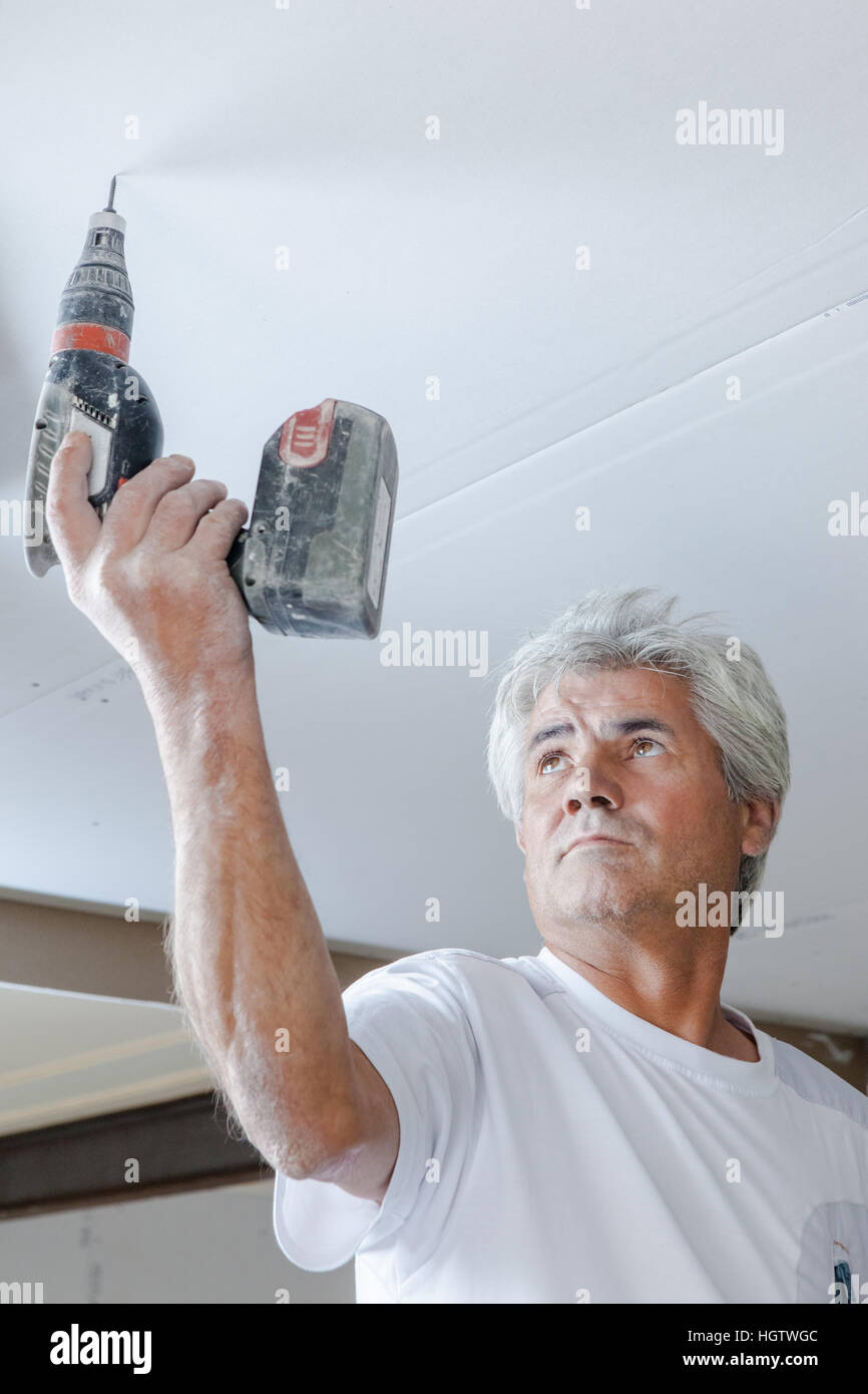 Builder drilling hole in ceiling Stock Photo - Alamy