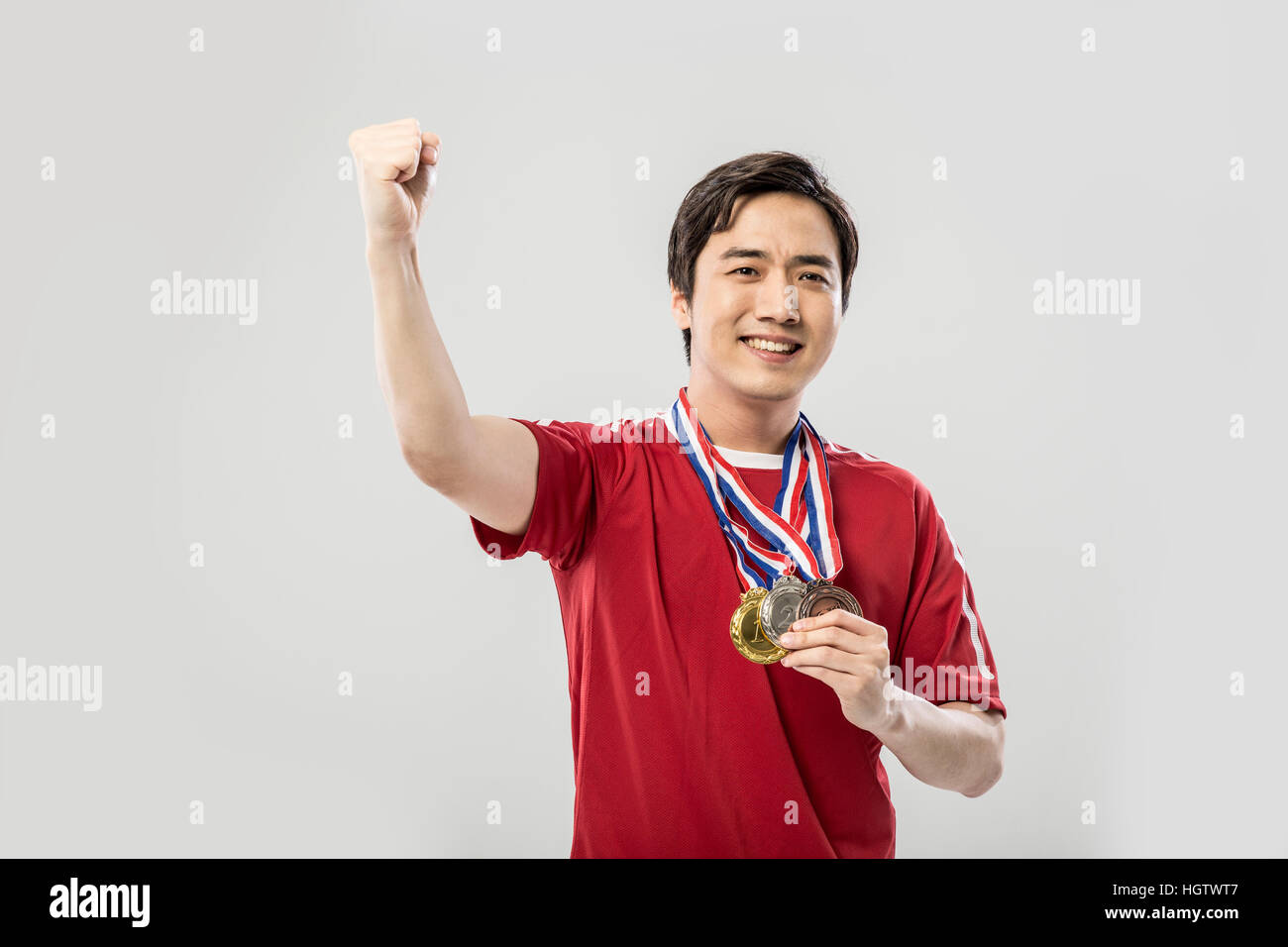 Portrait of young smiling male Korean sports player with medal cheering ...