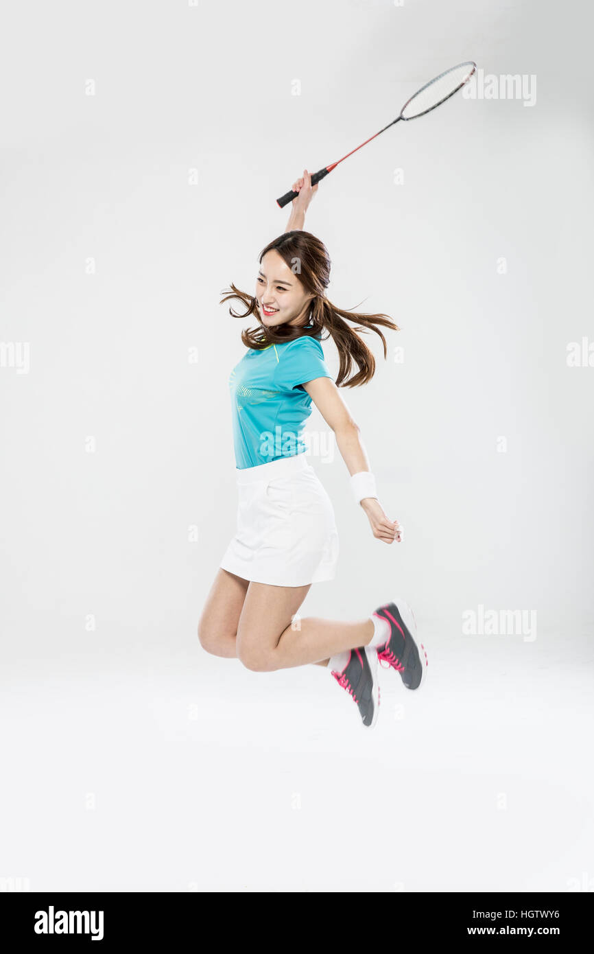 Side view of young smiling female badminton player jumping Stock Photo ...