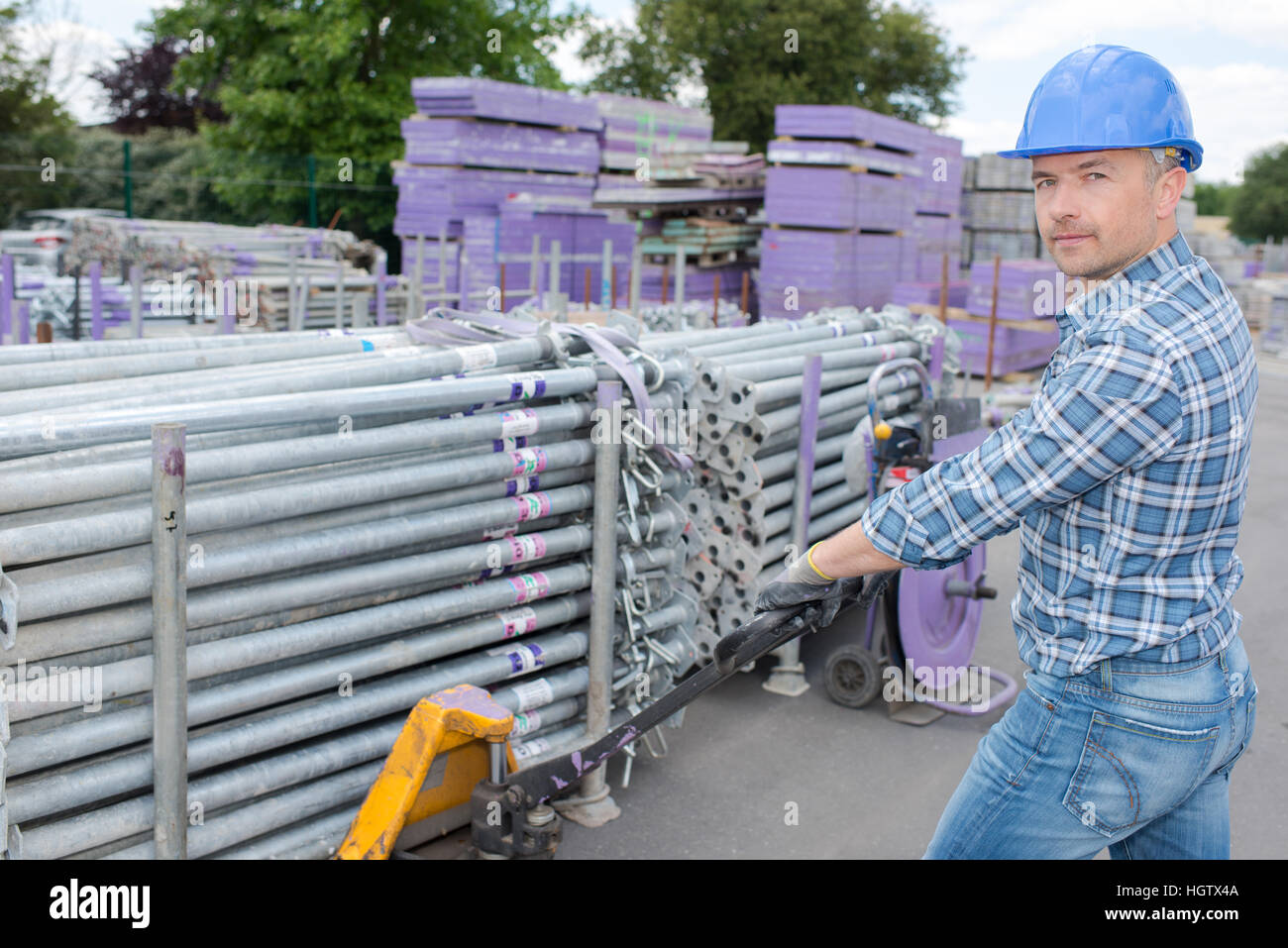 Worker pulling pallet of metal tubes Stock Photo - Alamy