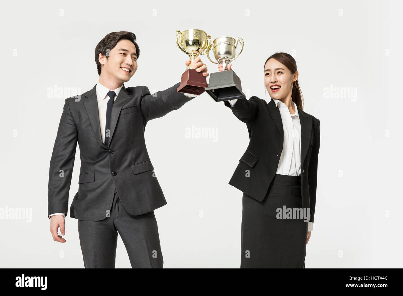 Young smiling business people cheering with trophies Stock Photo - Alamy