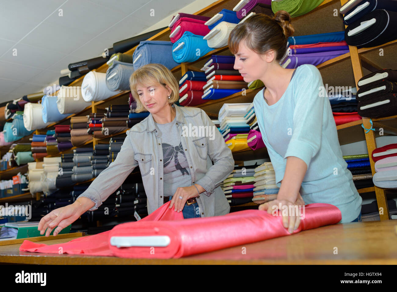 Women unfolding roll of material Stock Photo - Alamy