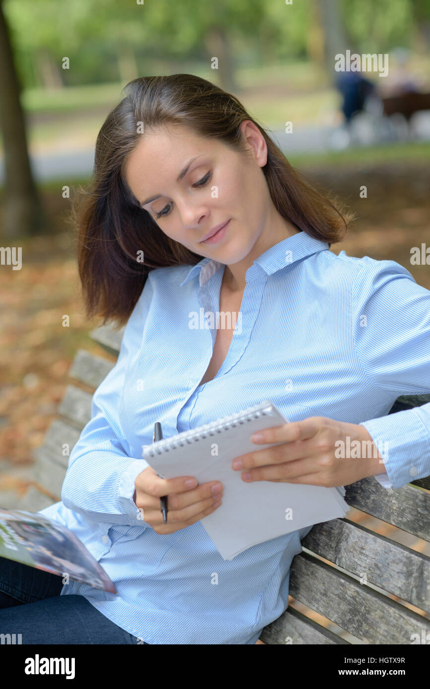 Woman sat on park bench holding notepad Stock Photo - Alamy