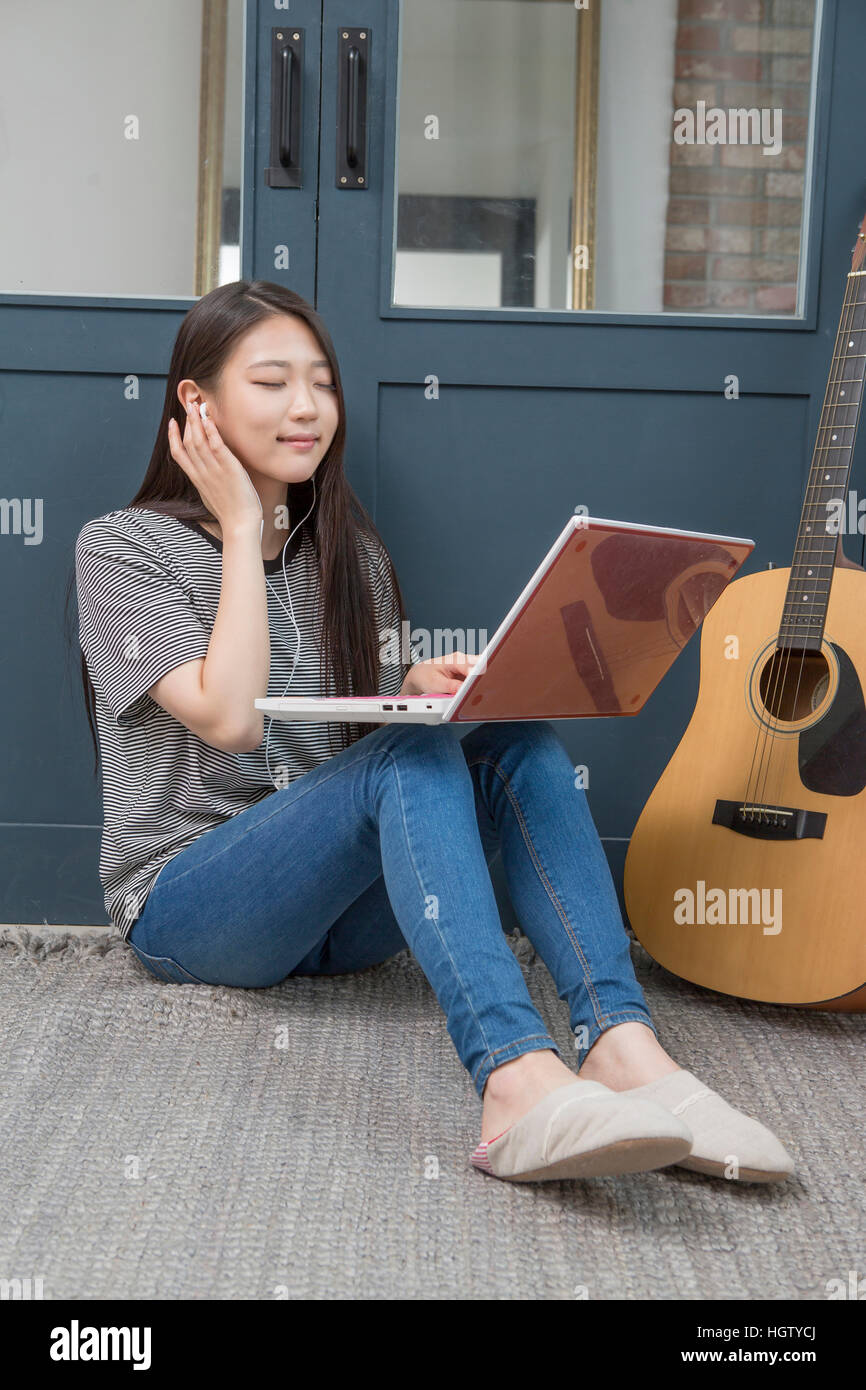 Young smiling woman using notebook computer listening to music with her ...