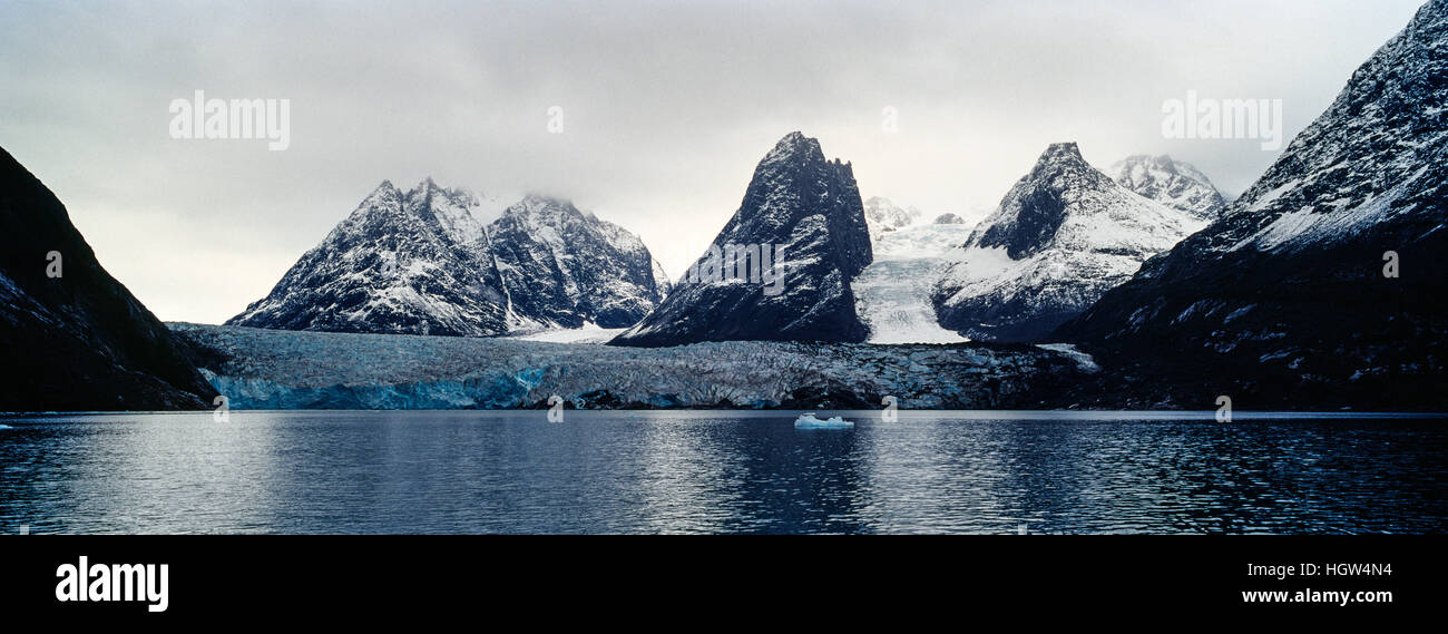 Jagged mountain peaks rise above a glacier in a arctic fjord Stock ...