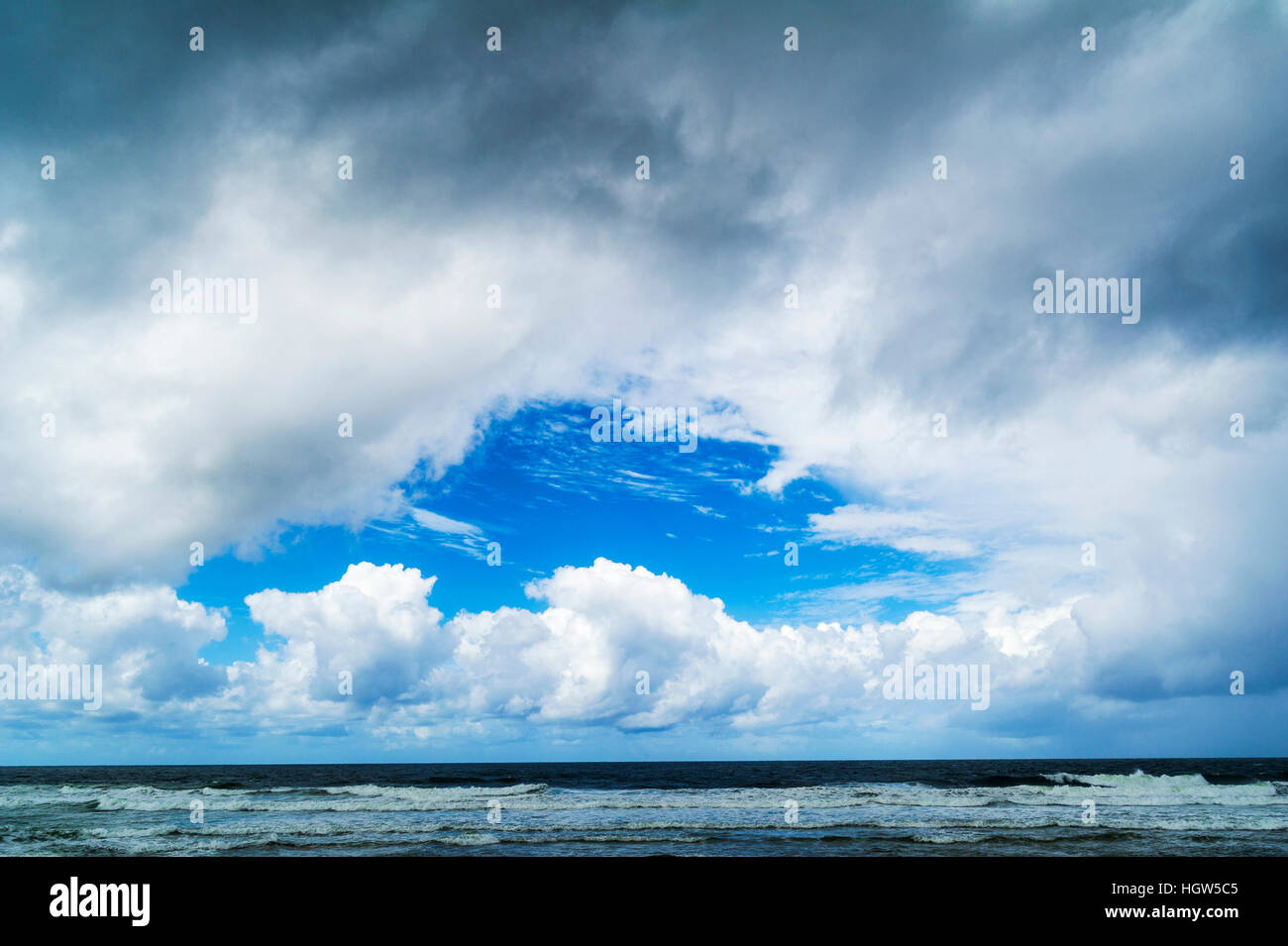 A patch of blue sky appears over an ocean during a storm Stock Photo ...