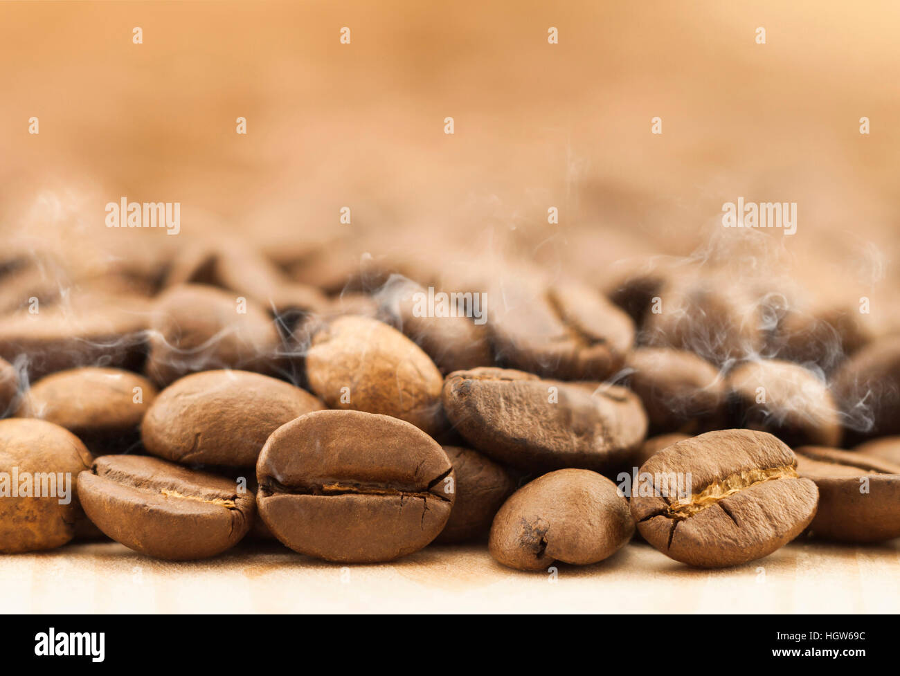 Brown coffee beans with white smoke vapour on yellow textured wooden ...