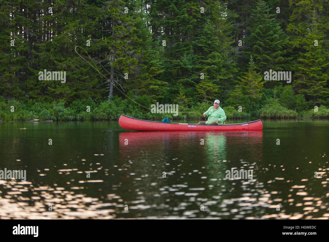 A man fly-fishing on Little Berry Pond in Maine's Northern Forest. Cold ...