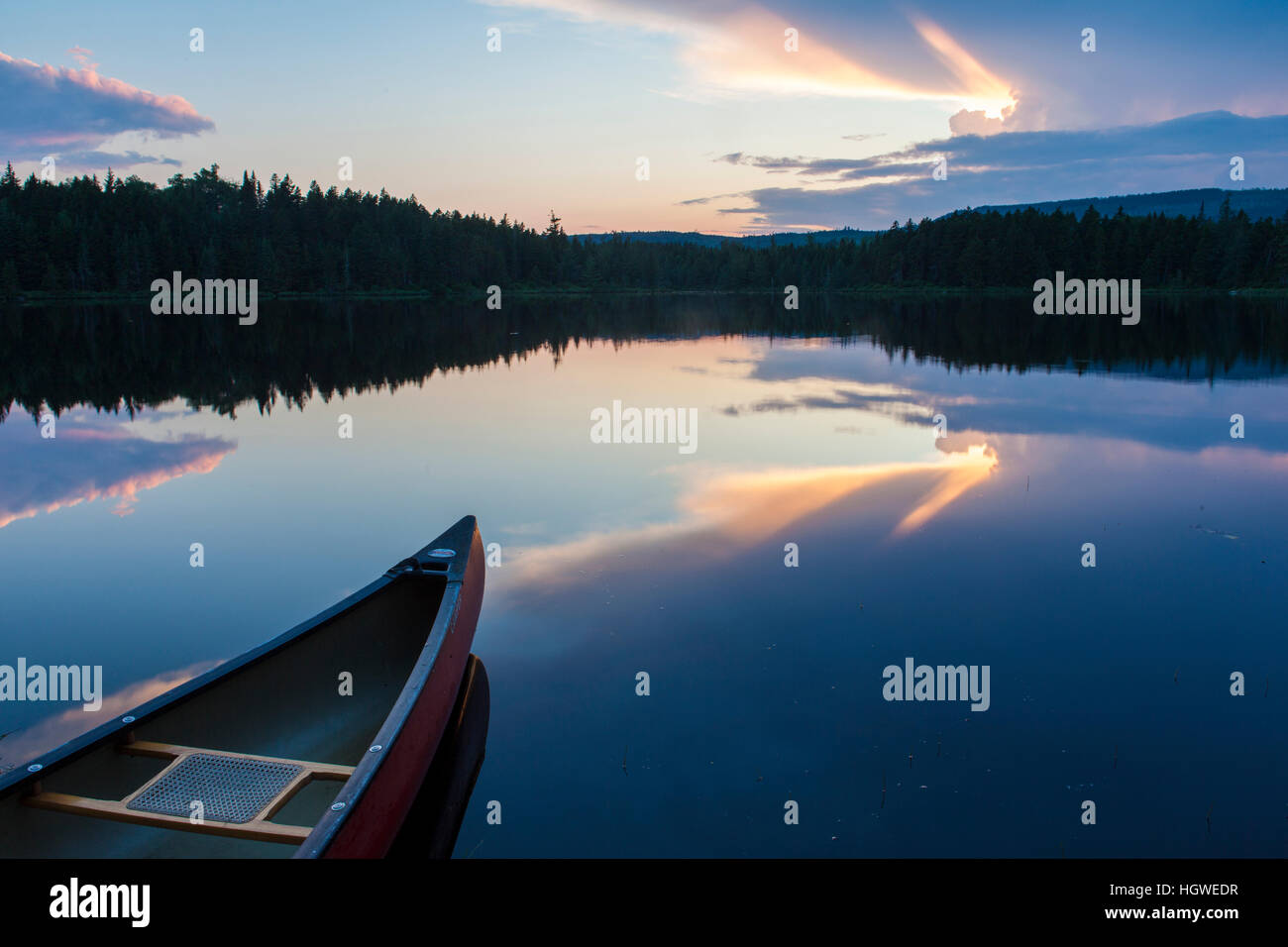 A canoe on Little Berry Pond in Maine's Northern Forest. Sunset. Cold ...