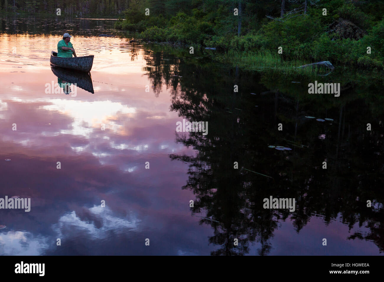 A man canoeing at sunrise on Little Berry Pond in Maine's Northern ...