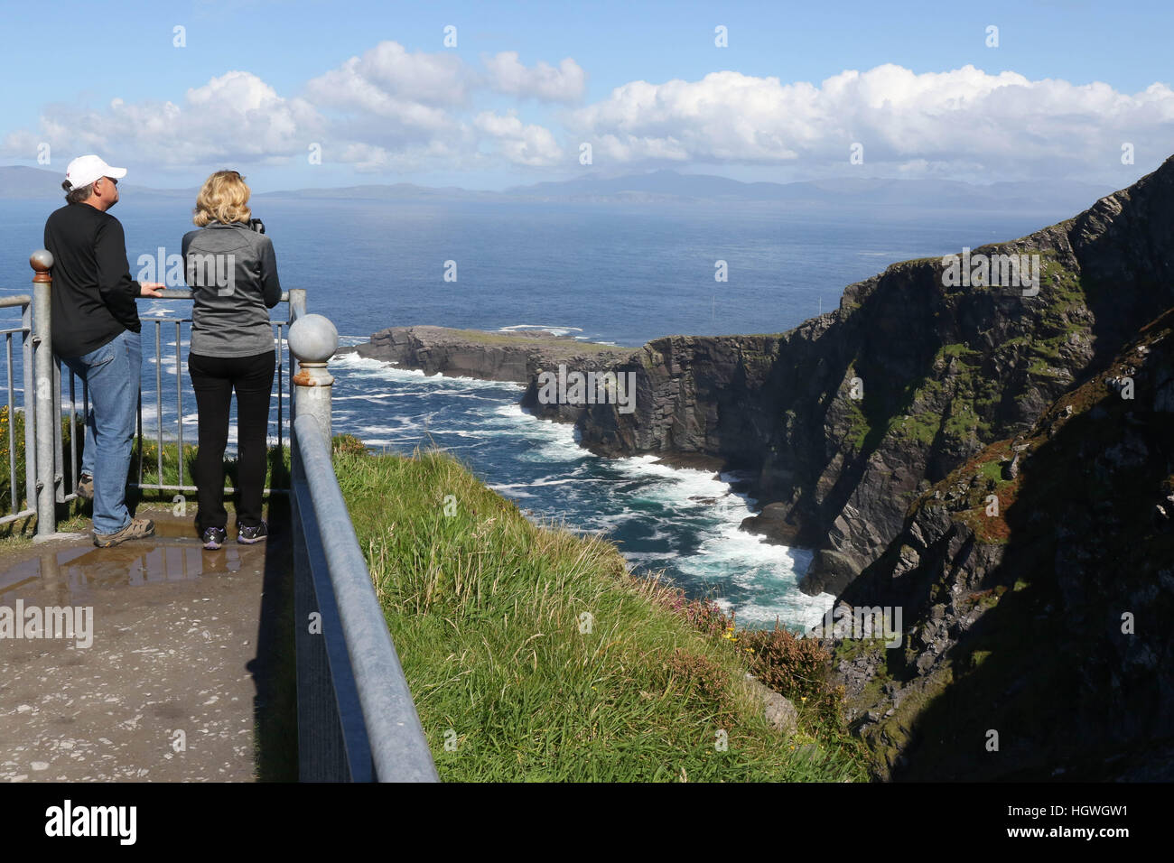 Man and women looking out from clifftop viewpoint in Ireland with white ...