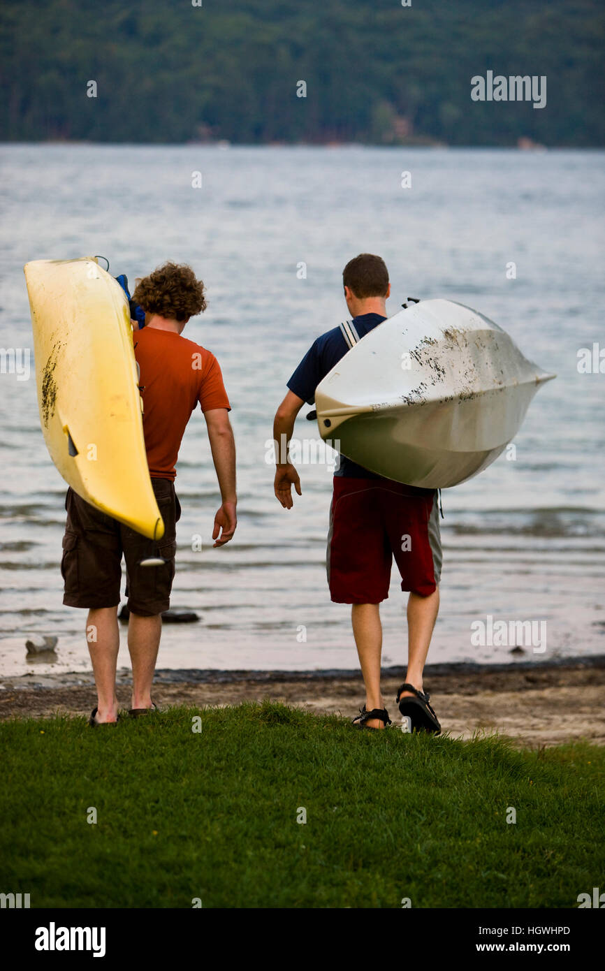 Two men carry their kayaks after paddling on Lake Sunapee at Mount ...