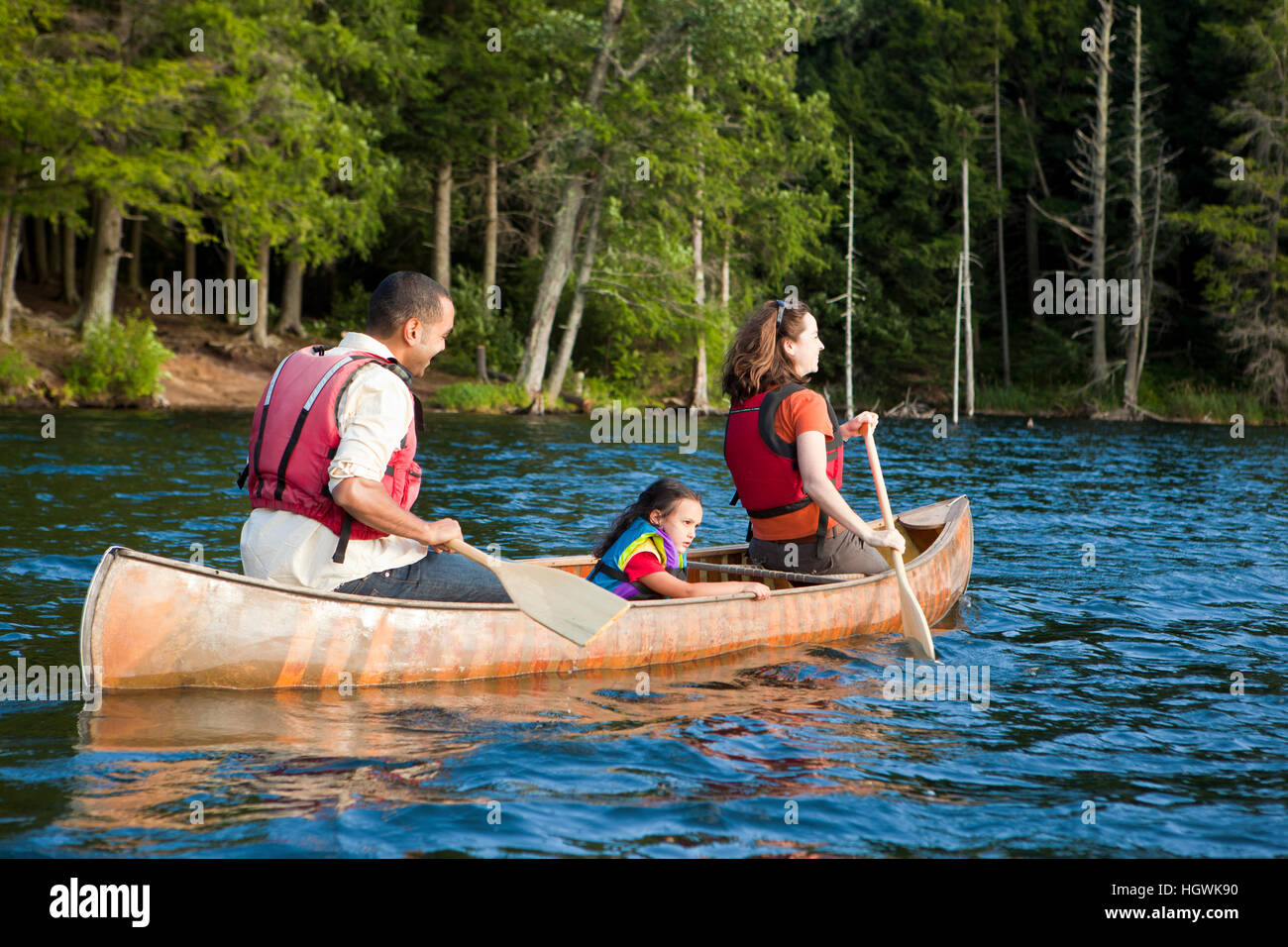 A man, woman, and young girl canoe on Zack Woods Pond in Hyde Park ...