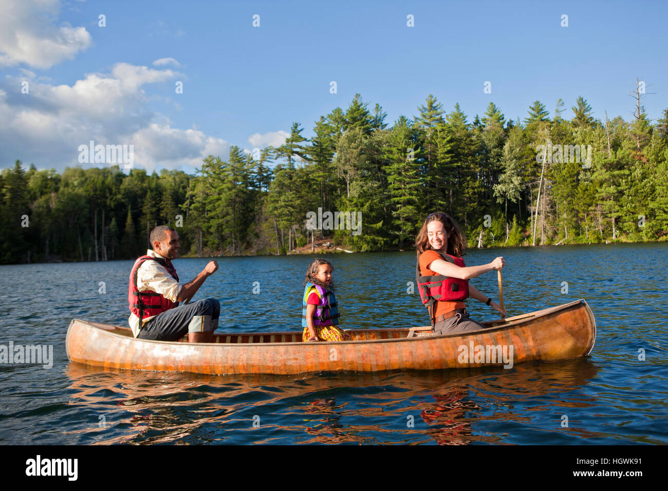 A man, woman, and young girl canoe on Zack Woods Pond in Hyde Park ...
