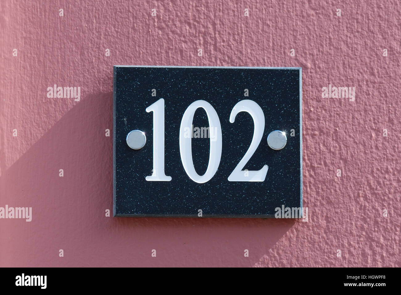 House Number 102 sign on wall painted red Stock Photo - Alamy