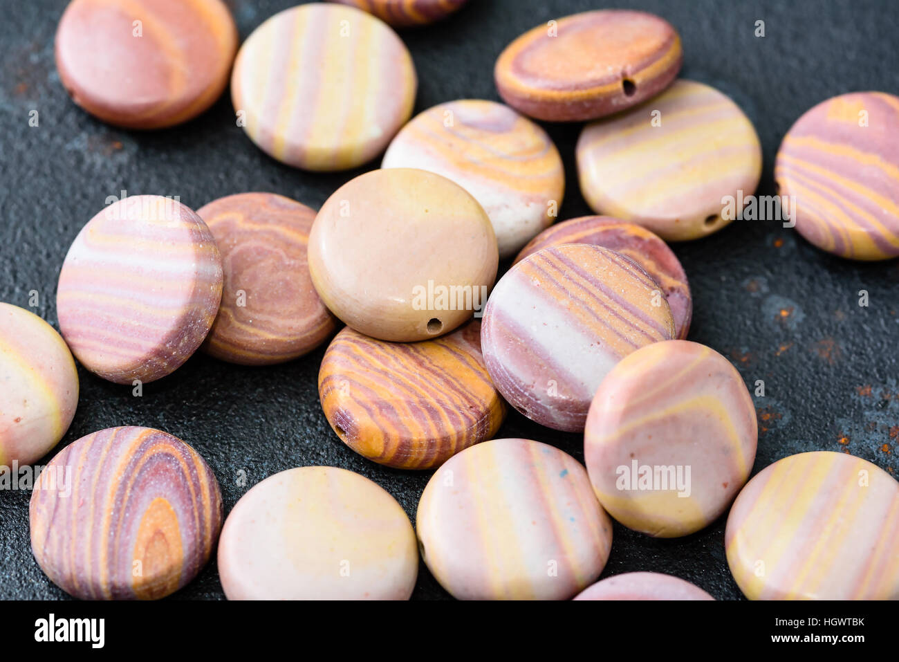Collection of multicolored coin shaped hickoryite beads on black cast ...